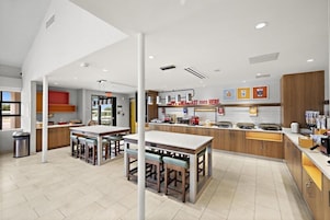 Uma cozinha moderna com ilha central, banquetas e balcão de refeições.