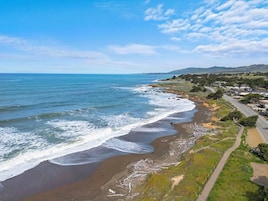 Uma estrada costeira com praia, oceano e área residencial.