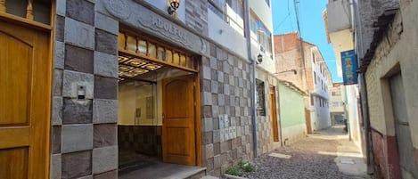Um beco estreito com um edifício de fachada em pedra e portas de madeira.
