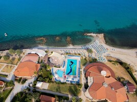 Vista aérea de um resort com piscina, área de praia e vários edifícios.