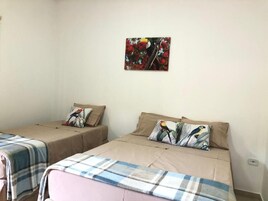 Quarto com duas camas, cada uma com travesseiro e cobertor.