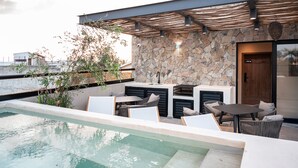 Uma área de piscina moderna ao ar livre, com paredes de pedra, um pérgola e mobiliário de exterior.