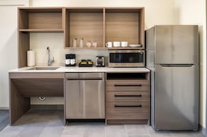 Uma cozinha moderna com eletrodomésticos de aço inoxidável, armários de madeira e máquina de lavar louça embutida.