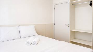 Quarto de hotel com cama, guarda-roupa e prateleira.