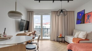 Uma sala de estar moderna com área de jantar, sofá, TV e varanda com vista.