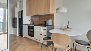 Uma cozinha moderna com armários de madeira, forno embutido e uma mesa de jantar redonda com cadeiras.