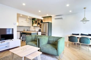 Uma sala de estar moderna com sofá, televisão e área de jantar.