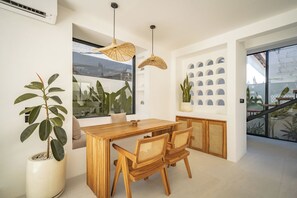 Uma área de refeições moderna com mesa e cadeiras de madeira, janelas amplas e vista para o exterior.