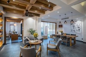 Uma sala de estar ampla com teto alto, vigas de madeira, mesa de jantar e sofá.