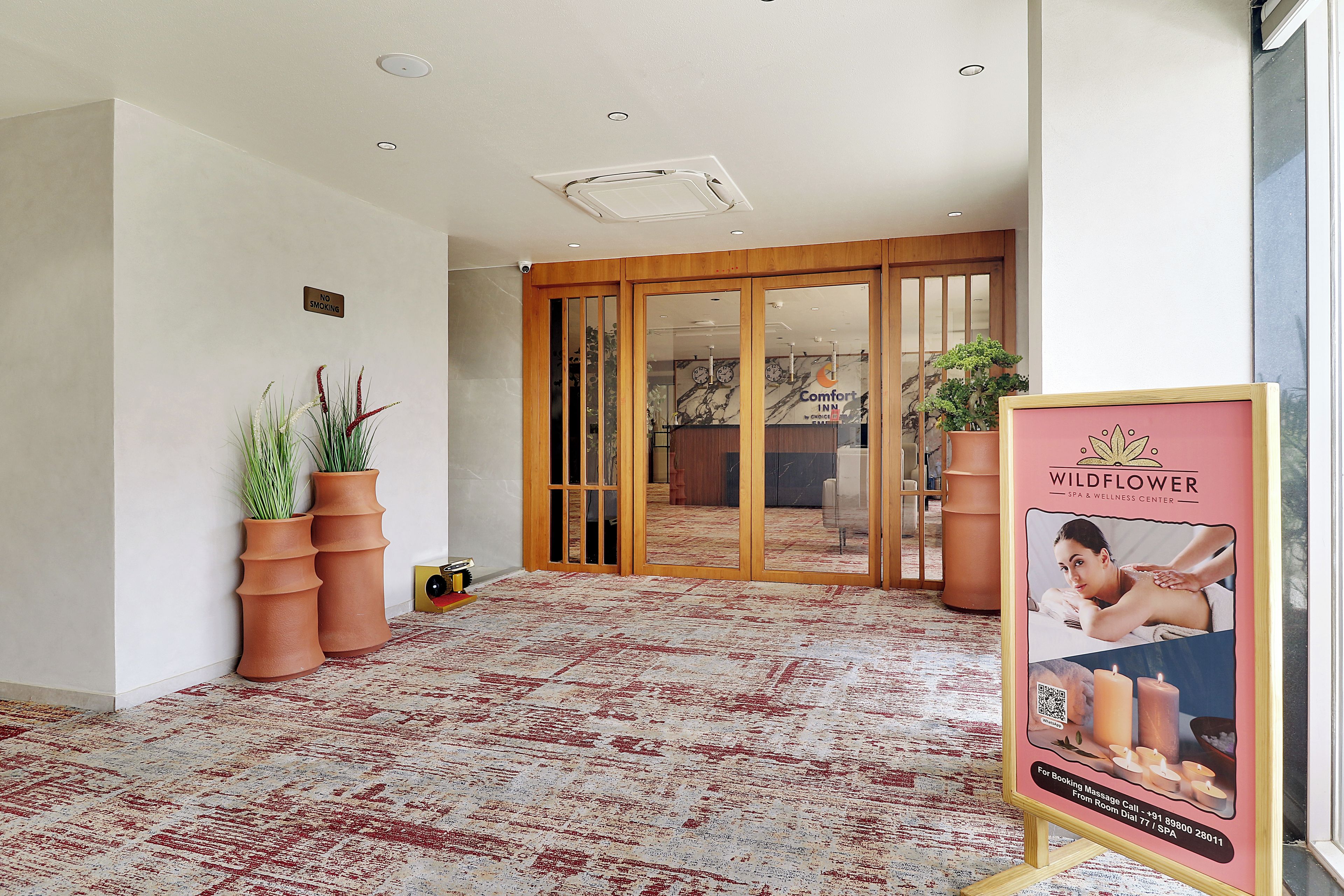 Um hall de hotel com carpete estampado, um aviso de 'Proibido Fumar' e a placa 'Comfort Inn'.