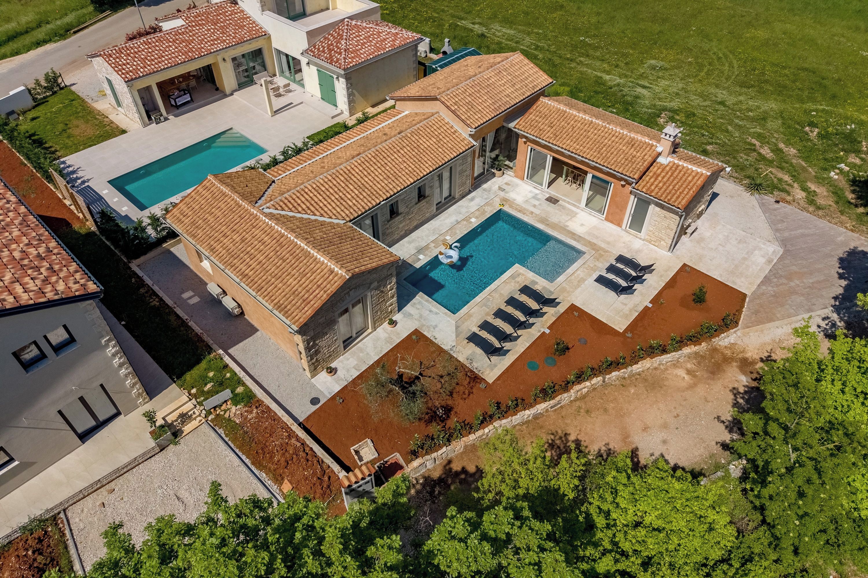 Um imóvel residencial com piscina, vários edifícios e gramado bem cuidado.