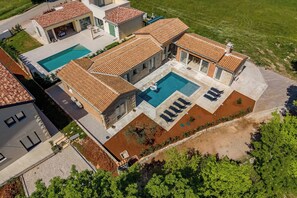 Um imóvel residencial com piscina, vários edifícios e gramado bem cuidado.