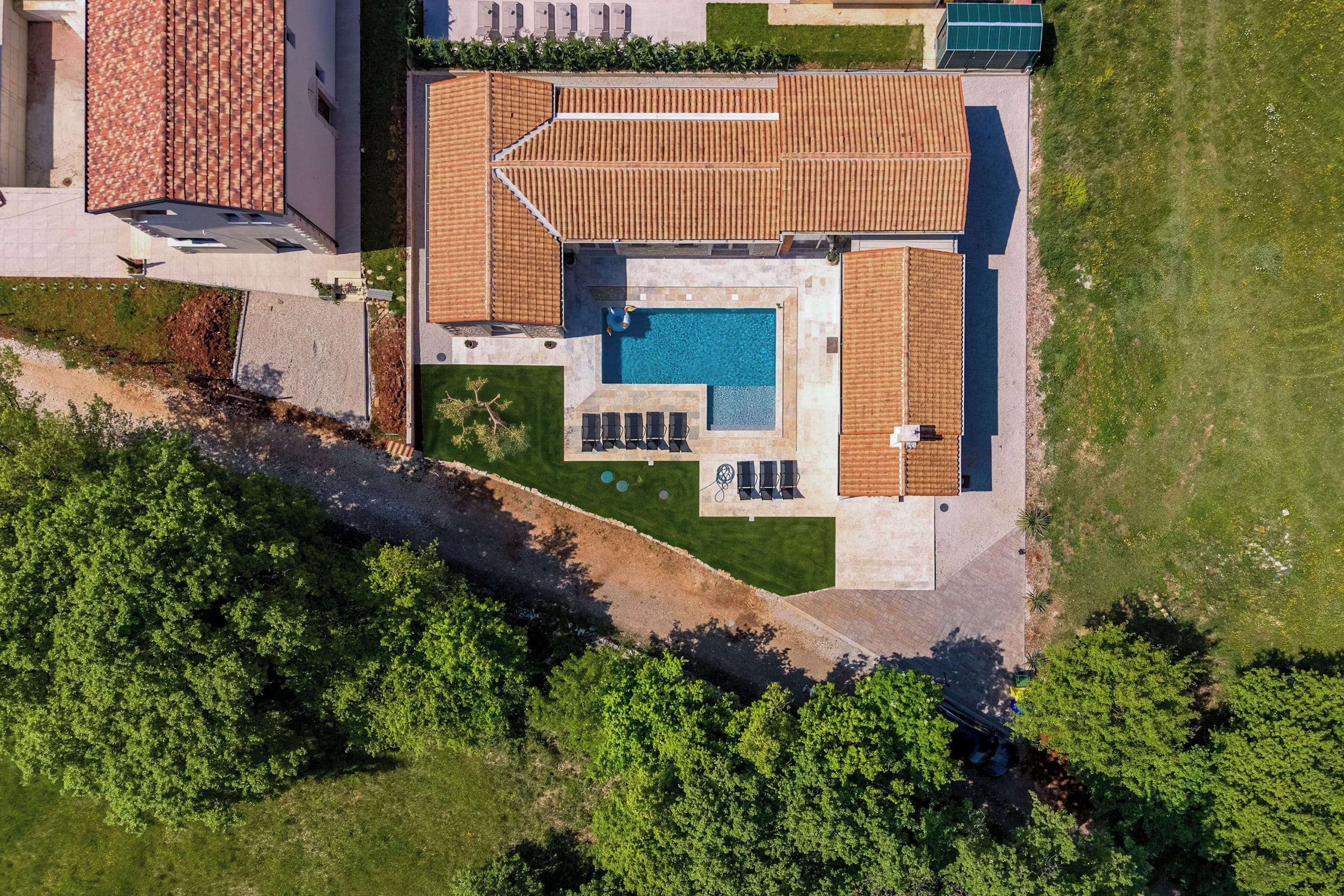 Vista aérea de uma propriedade residencial com piscina, área de pátio e um grande jardim.