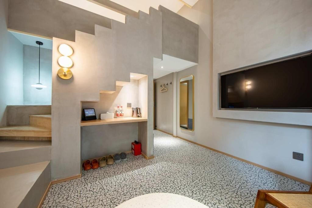 Um interior moderno com uma escada, uma TV de tela plana na parede e um sapateiro com vários pares de sapatos.