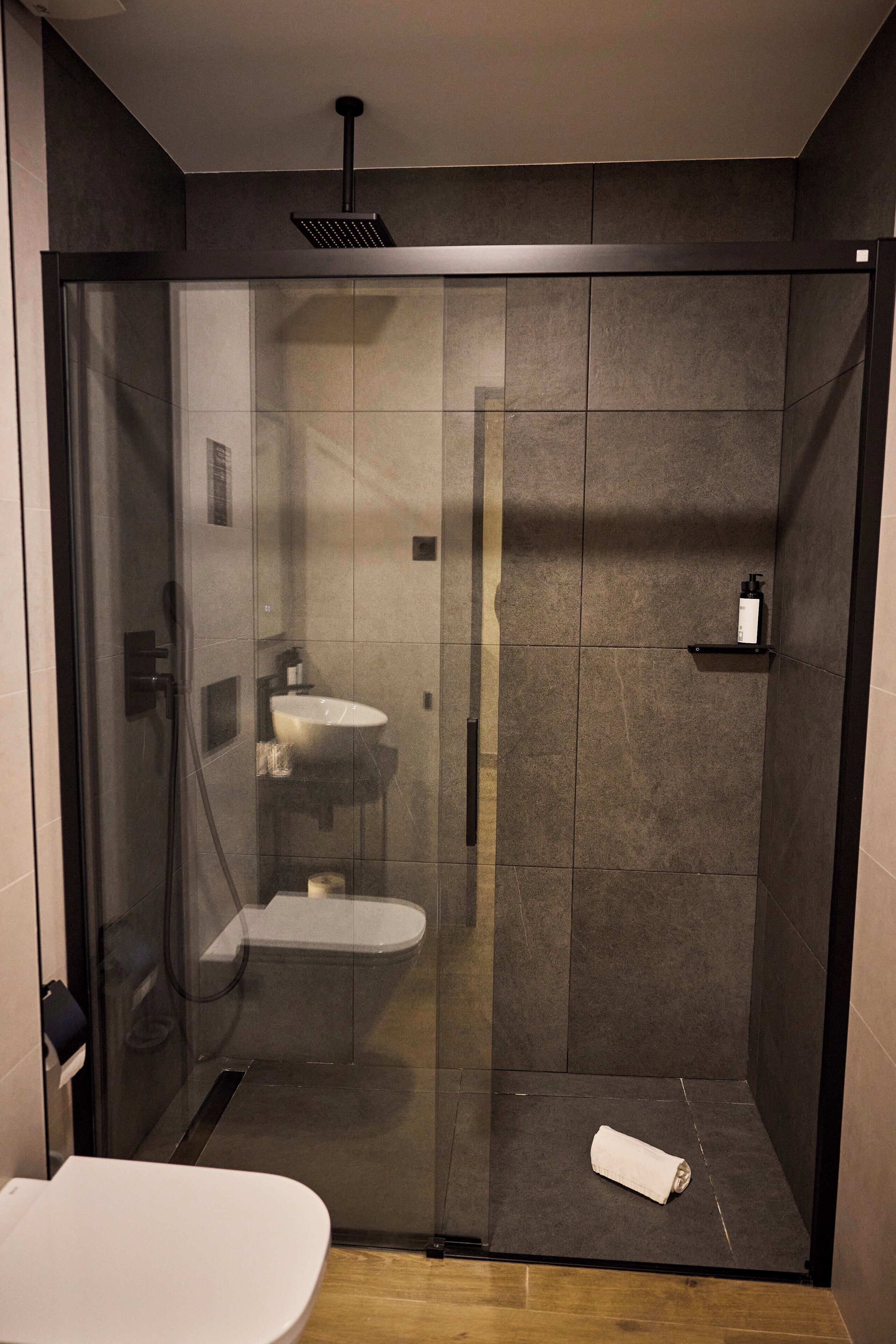 Uma casa de banho moderna com chuveiro em cabine de vidro, lavatório branco e sanita.