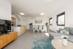 Uma sala de estar moderna com televisão, sofá e área de refeições.