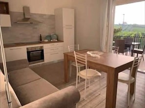 Uma cozinha moderna com área de refeições, um sofá e vista para o exterior.