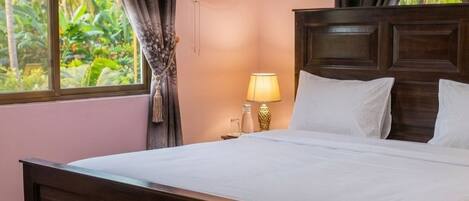 Quarto com uma cama grande, um ventilador de cabeceira e cortinas.
