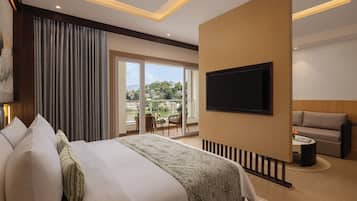 Quarto de hotel com uma cama grande, TV de tela plana, varanda com vista e um sofá.