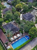 Bairro residencial com várias casas, piscina e vegetação exuberante.