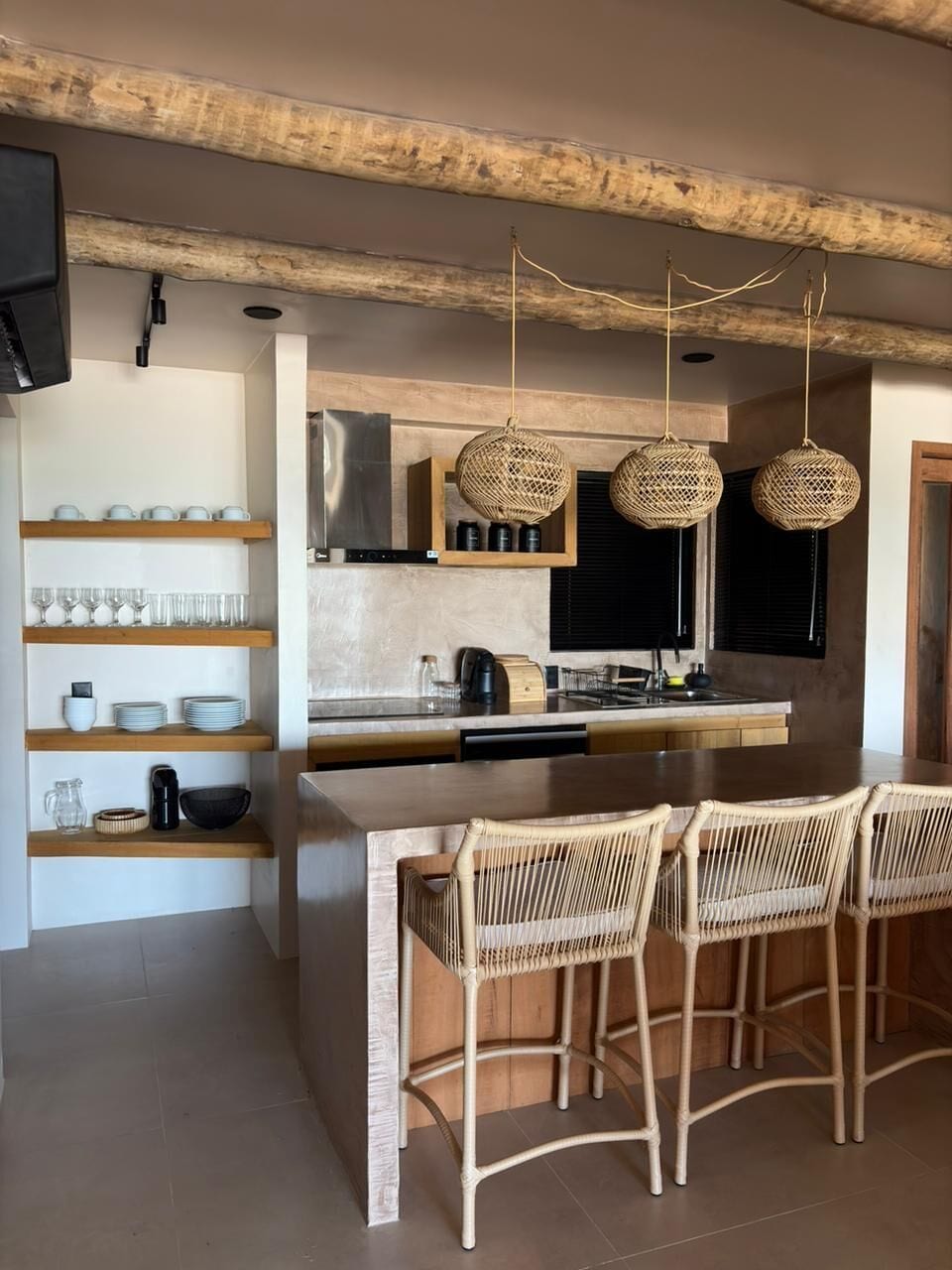Cozinha com ilha central, cadeiras de vime e luminárias pendentes.