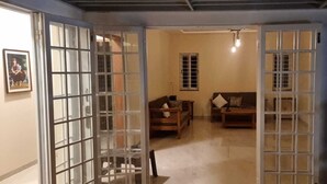 Um quarto com sofá de madeira, uma mesa pequena e uma janela.