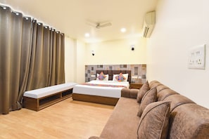 Quarto com cama, um banco, sofá, ventilador de teto, ar-condicionado e luminária na parede.