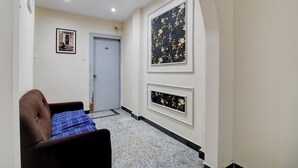 Um corredor com uma porta identificada como '201', um quadro na parede e um ventilador de teto.