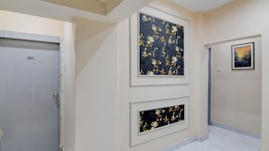 Um corredor com duas obras de arte floral emolduradas nas paredes, uma porta com a inscrição '303' e piso ladrilhado.