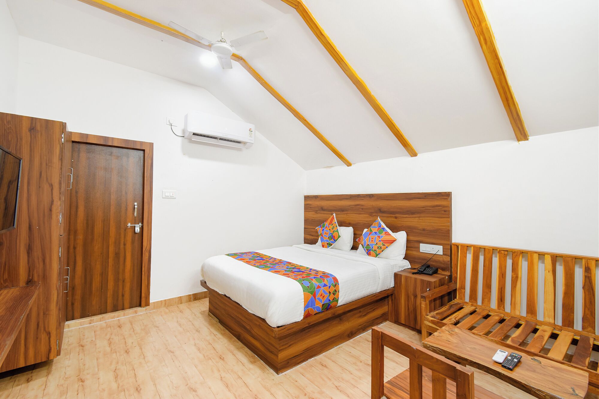 Quarto com cama de madeira, mesa de cabeceira, cadeira, ventilador de teto e ar condicionado.