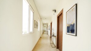 Um corredor com obras de arte emolduradas nas paredes, uma porta de madeira e piso de azulejos.