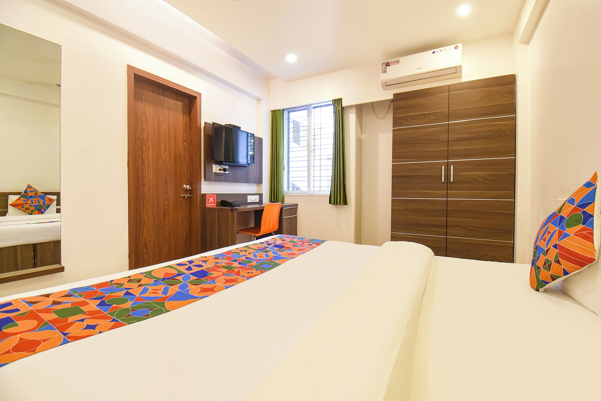 Quarto com cama, escrivaninha, televisão e guarda-roupa.