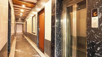 Um corredor com portas, um elevador e um visor digital.