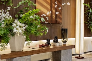 Uma mesa de madeira com objetos decorativos, incluindo um vaso com flores, uma pequena escultura e um livro.