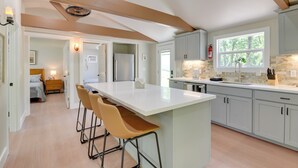 Uma cozinha moderna com uma ilha grande, banquetas e vista para o exterior.