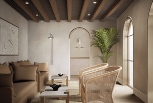 Um interior moderno com um sofá, uma mesa de centro, uma cadeira de vime, uma planta em vaso e uma luminária fixada na parede.