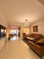 Uma sala de estar ampla com uma grande TV de tela plana, um sofá, uma mesa de centro e um quadro na parede.