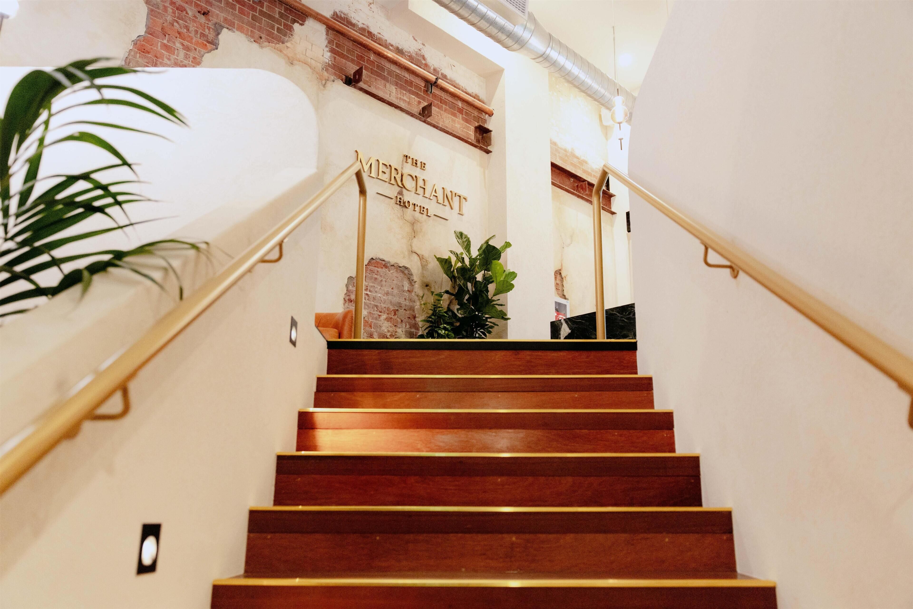 Uma escadaria leva a um quarto com uma placa que diz 'The Merchant Hotel'.
