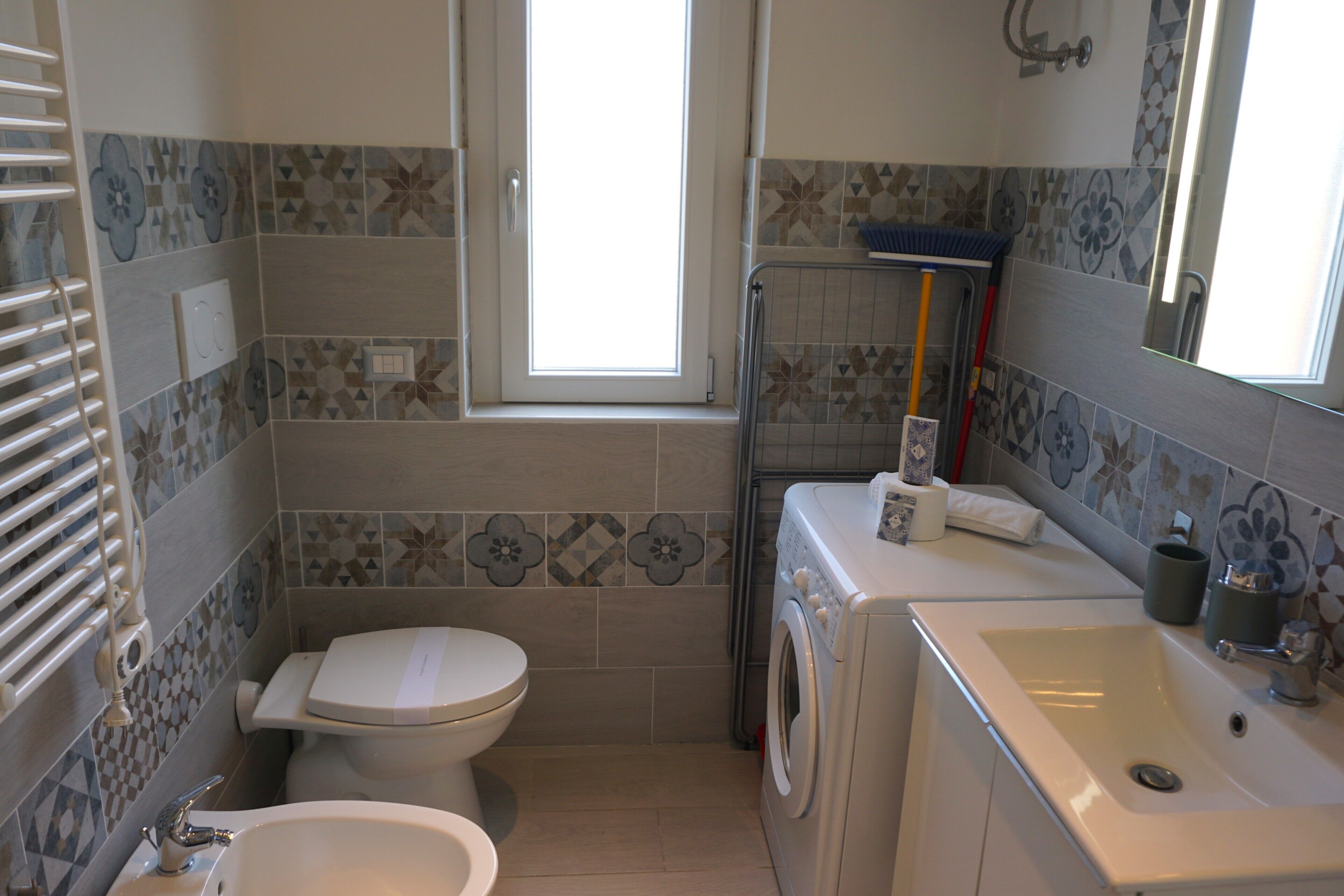 Casa de banho compacta com sanita, lavatório e máquina de lavar roupa.