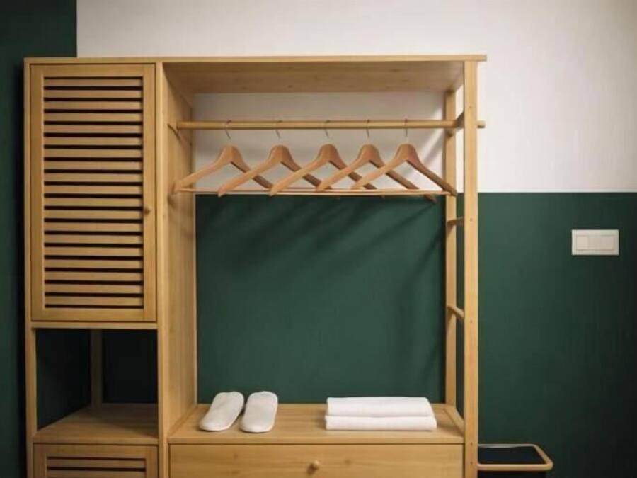 Guarda-roupa de madeira com espaço para pendurar, um prateleira para sapatos e uma toalha dobrada.