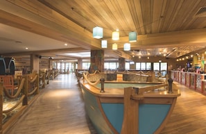 Interior de madeira com mesa de bilhar, áreas de estar e bar.