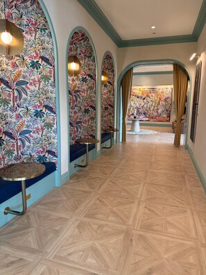 Um corredor com paredes estampadas, assentos azuis e piso de madeira.