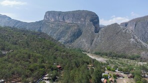 Paisagem montanhosa com um penhasco imponente e algumas casas dispersas.