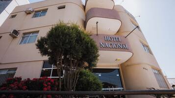 Um edifício de hotel com fachada curva, uma placa com a inscrição 'HOTEL NACIONAL' e uma árvore na frente.