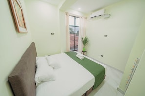 Quarto de hotel com uma cama, uma planta em vaso e um aparelho de ar condicionado.