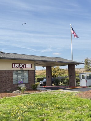 Um edifício de tijolos com uma placa indicando 'Legacy Inn' e uma bandeira americana em um mastro.