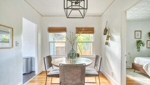 Uma sala de jantar com uma mesa redonda, quatro cadeiras, um vaso e um lustre.