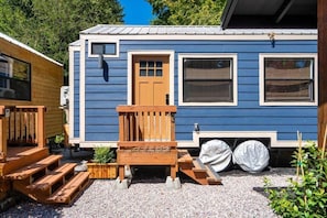 Uma casa móvel azul com deck de madeira, porta e janelas.