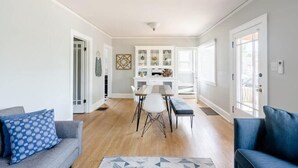 Uma sala de estar moderna com área de jantar, piso de madeira e vista para a cozinha.