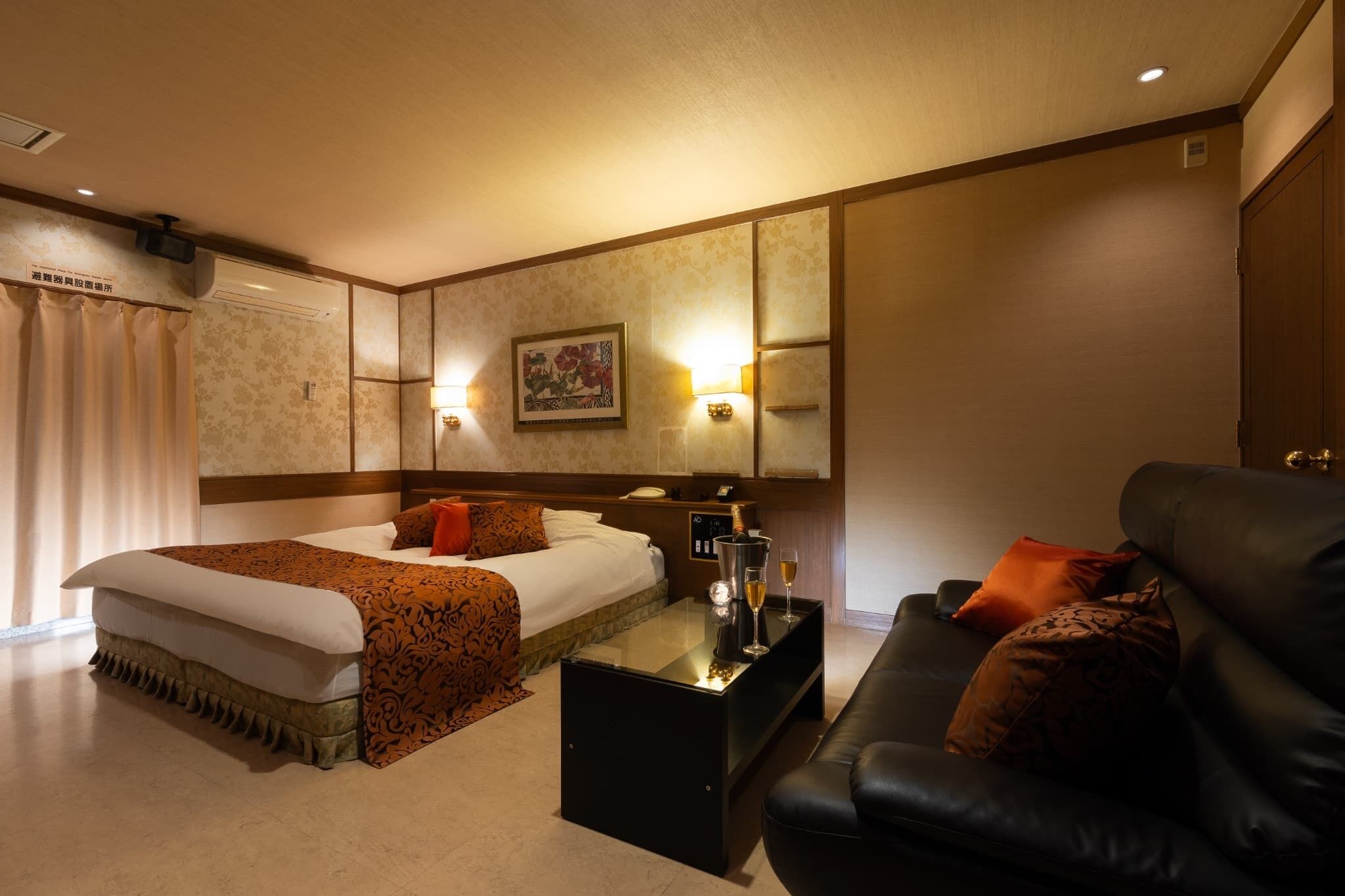 Quarto de hotel com cama, sofá, mesa de centro e televisão na parede.
